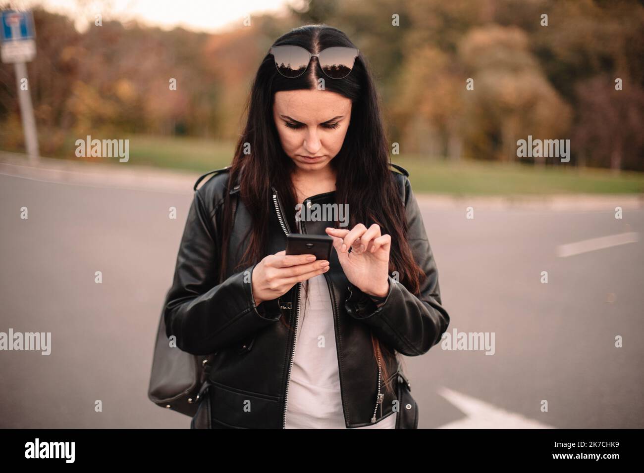 Serious young female traveler using smart phone while standing on the ...