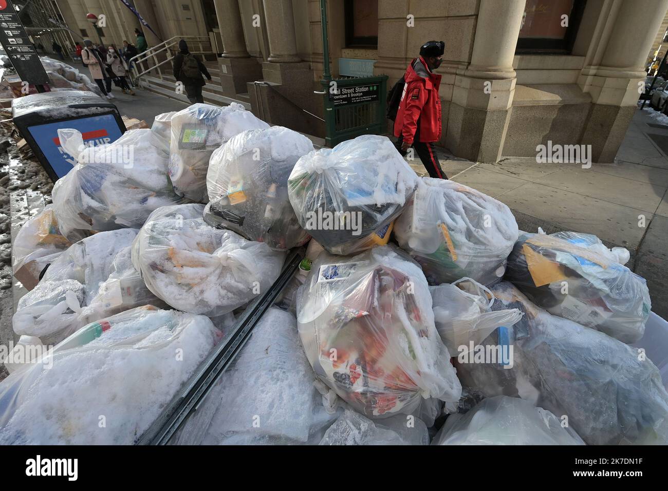 People walk past a piles of uncollected garbage in lower Manhattan ...