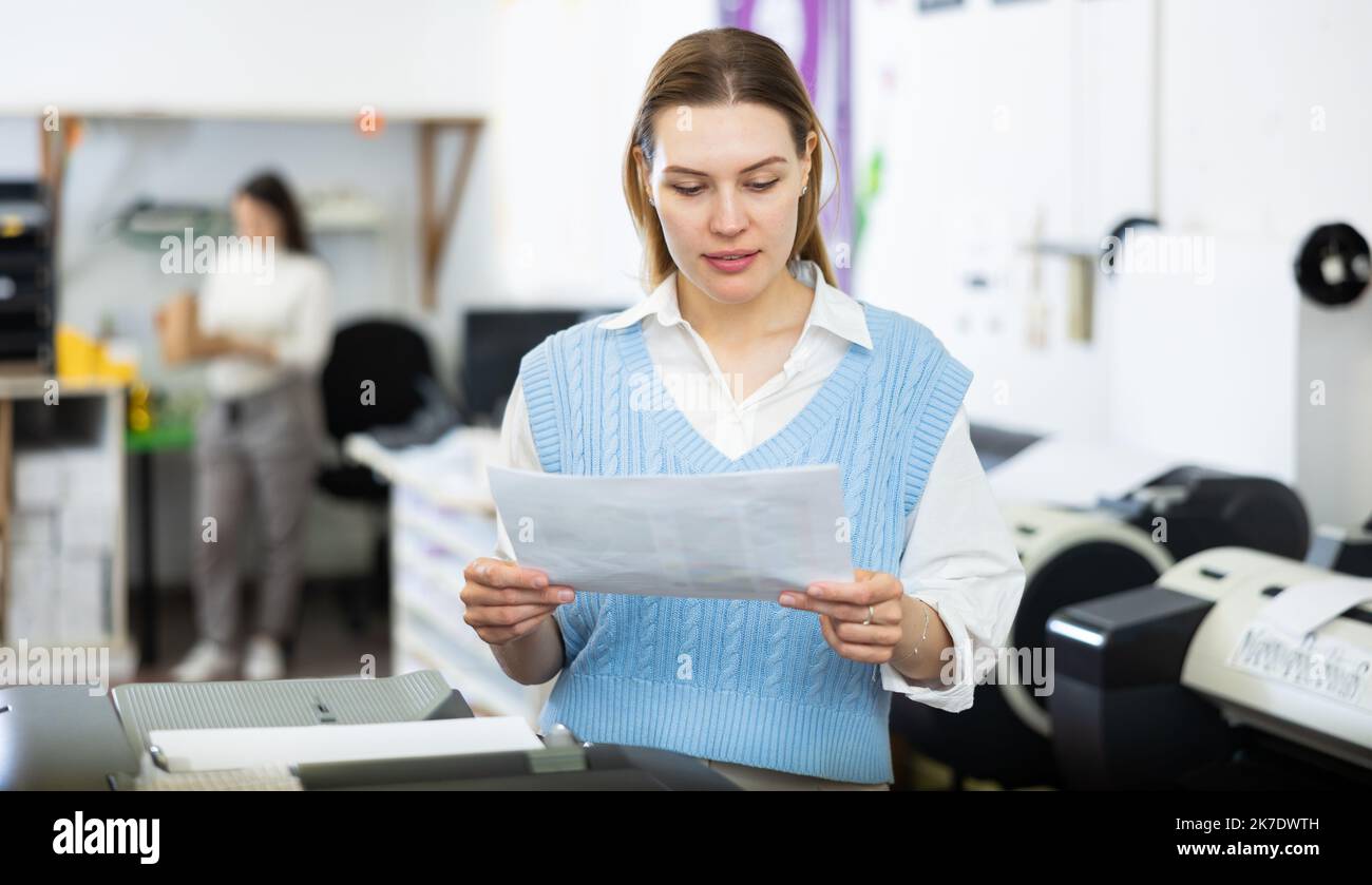 Printing office wokrer looking at paper Stock Photo - Alamy