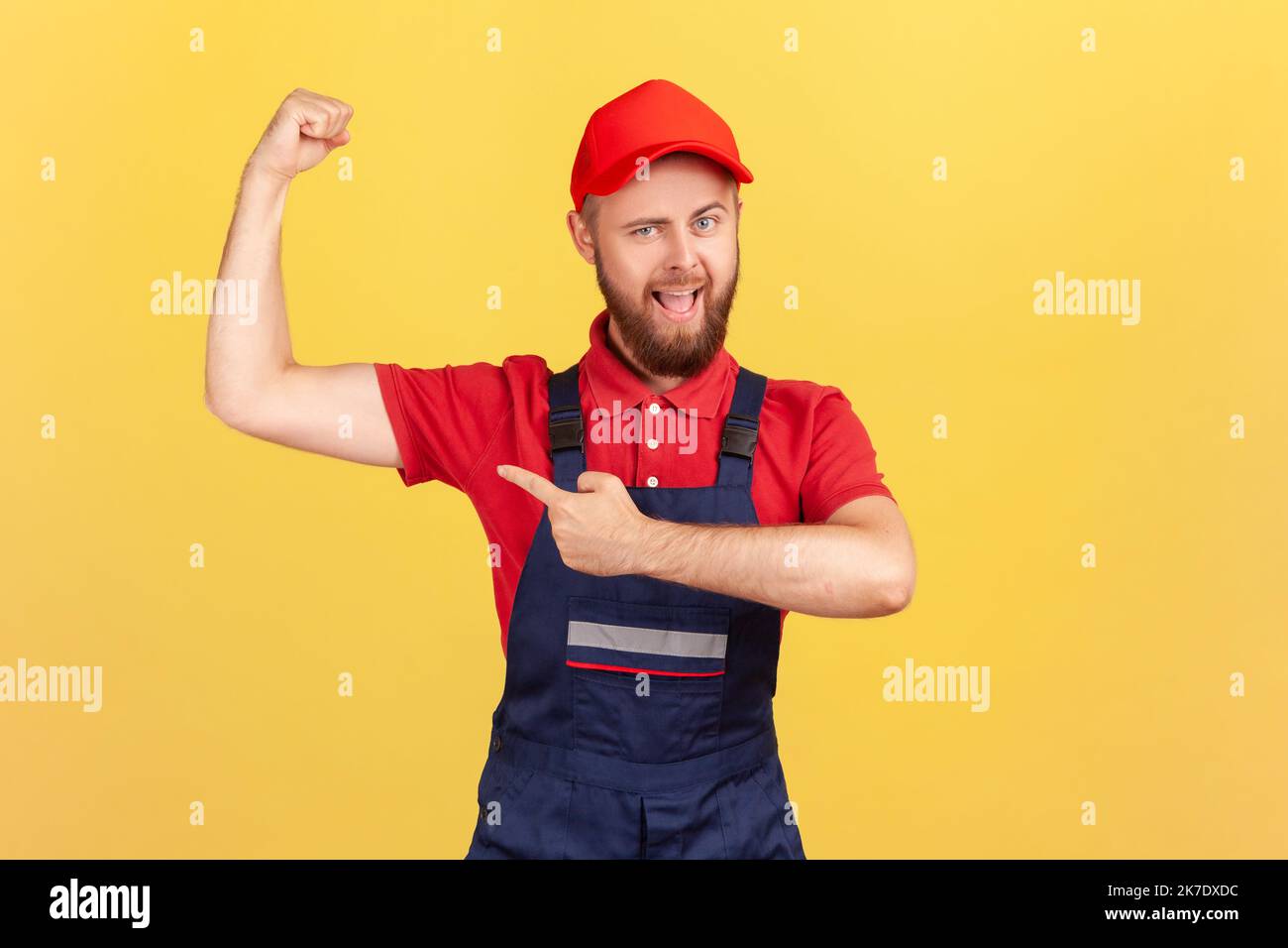 Portrait of proud strong worker man wearing blue uniform and red cap ...