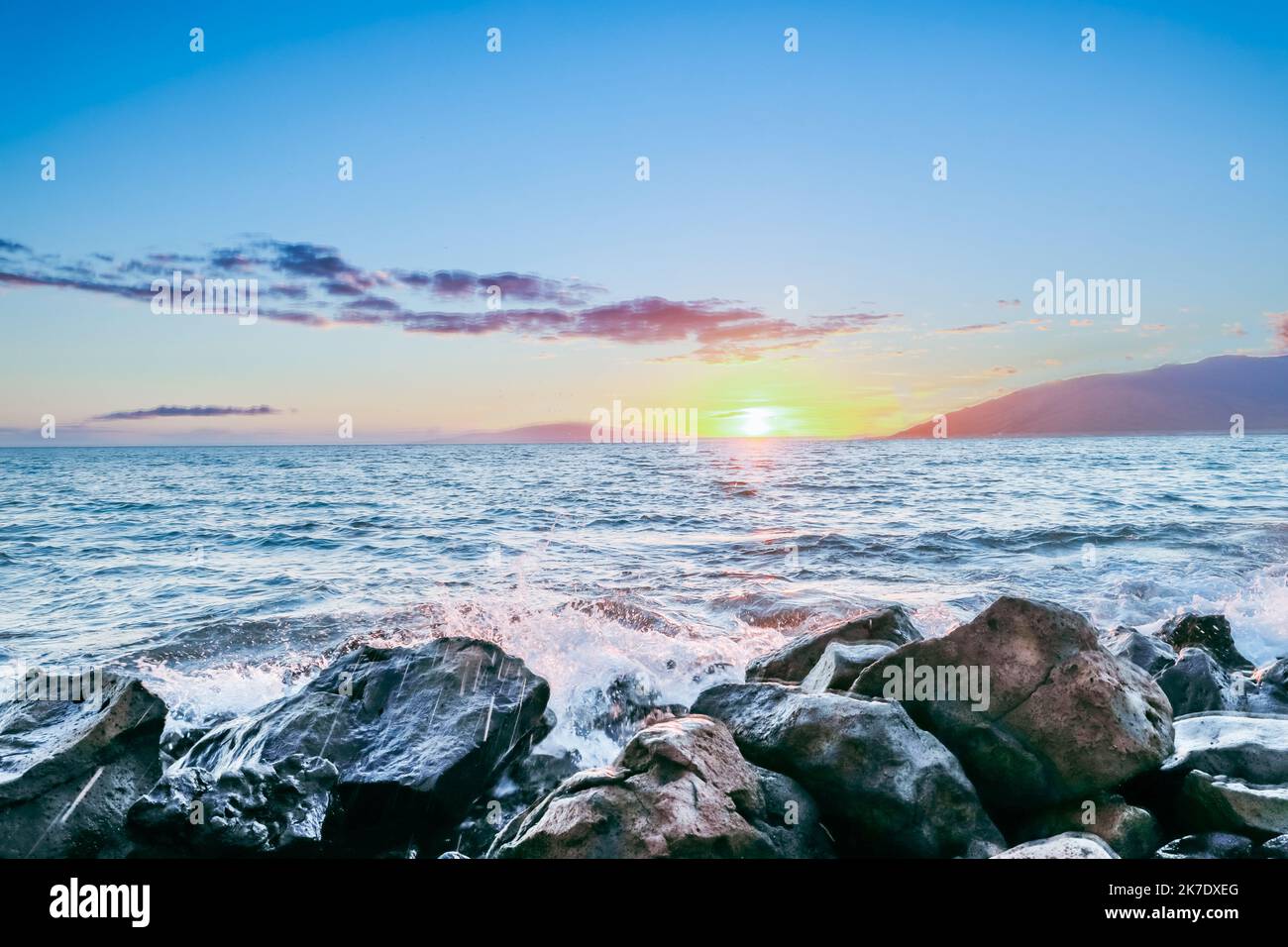Maui Hawaii at sunset with a low sun and rocks and a mountain Stock ...