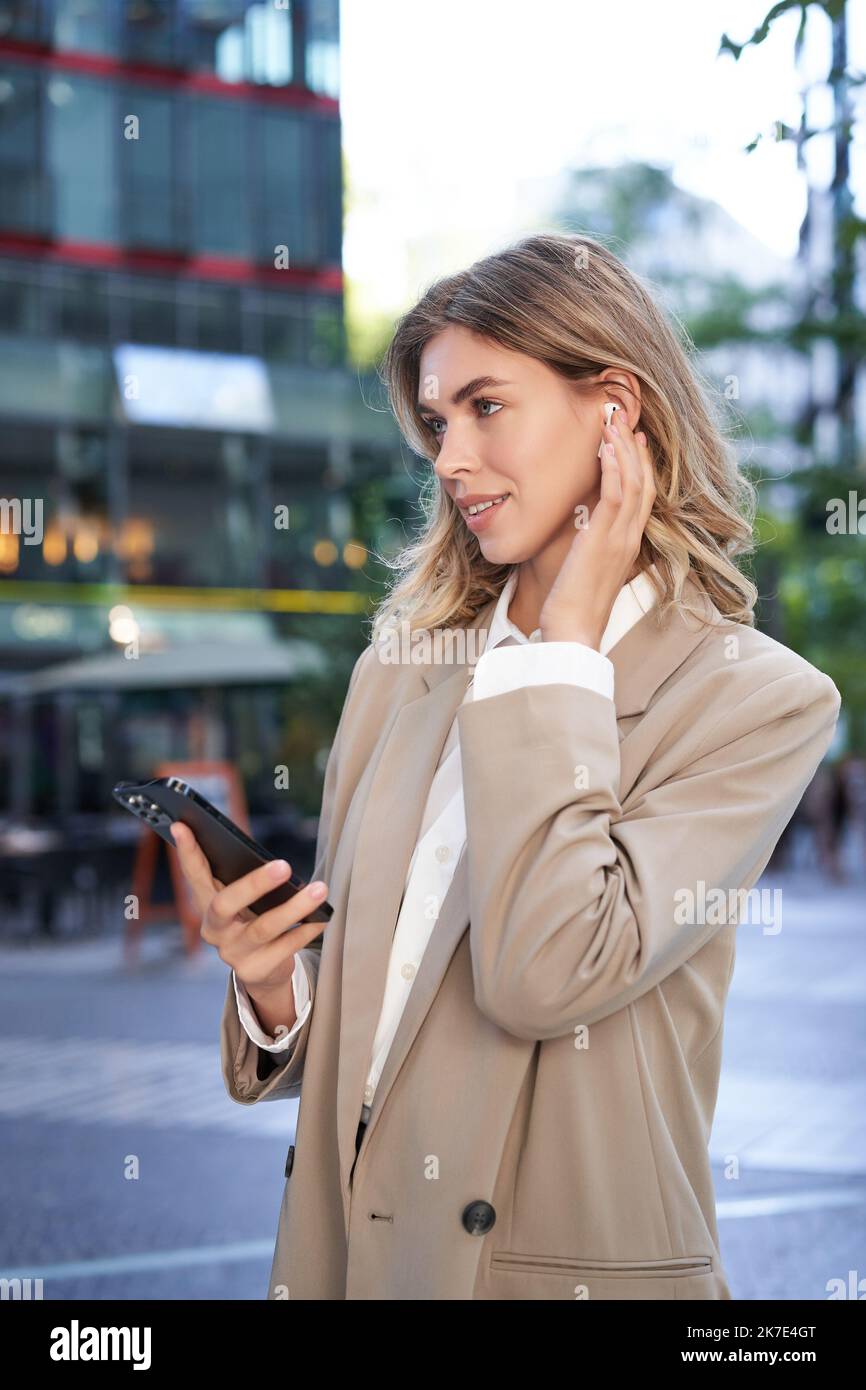 Vertical shot of businesswoman in suit, listening music in wireless ...