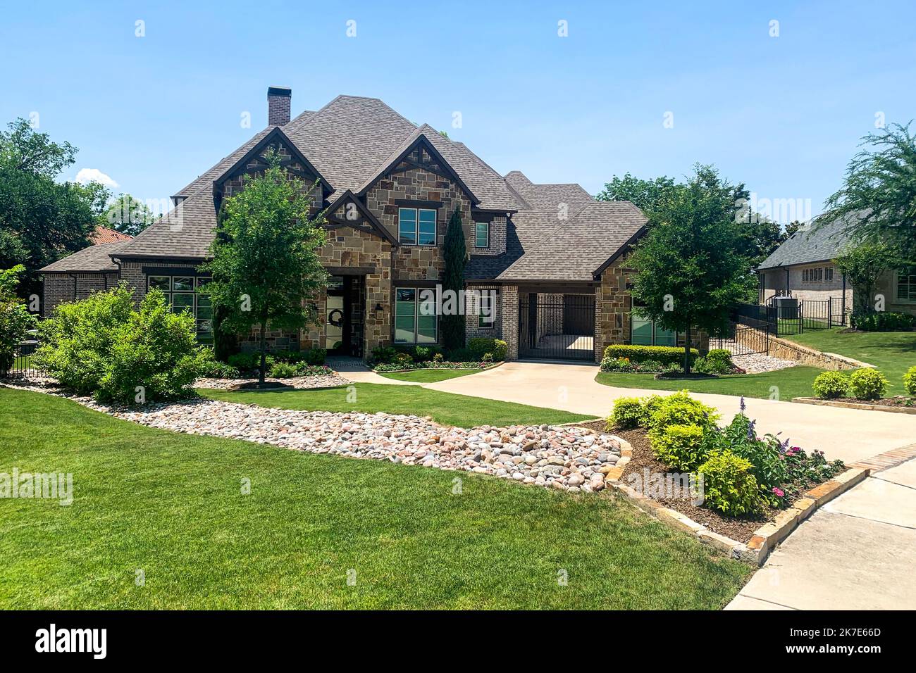Luxury house in suburban neighborhood with flowers, trees, bushes and ...