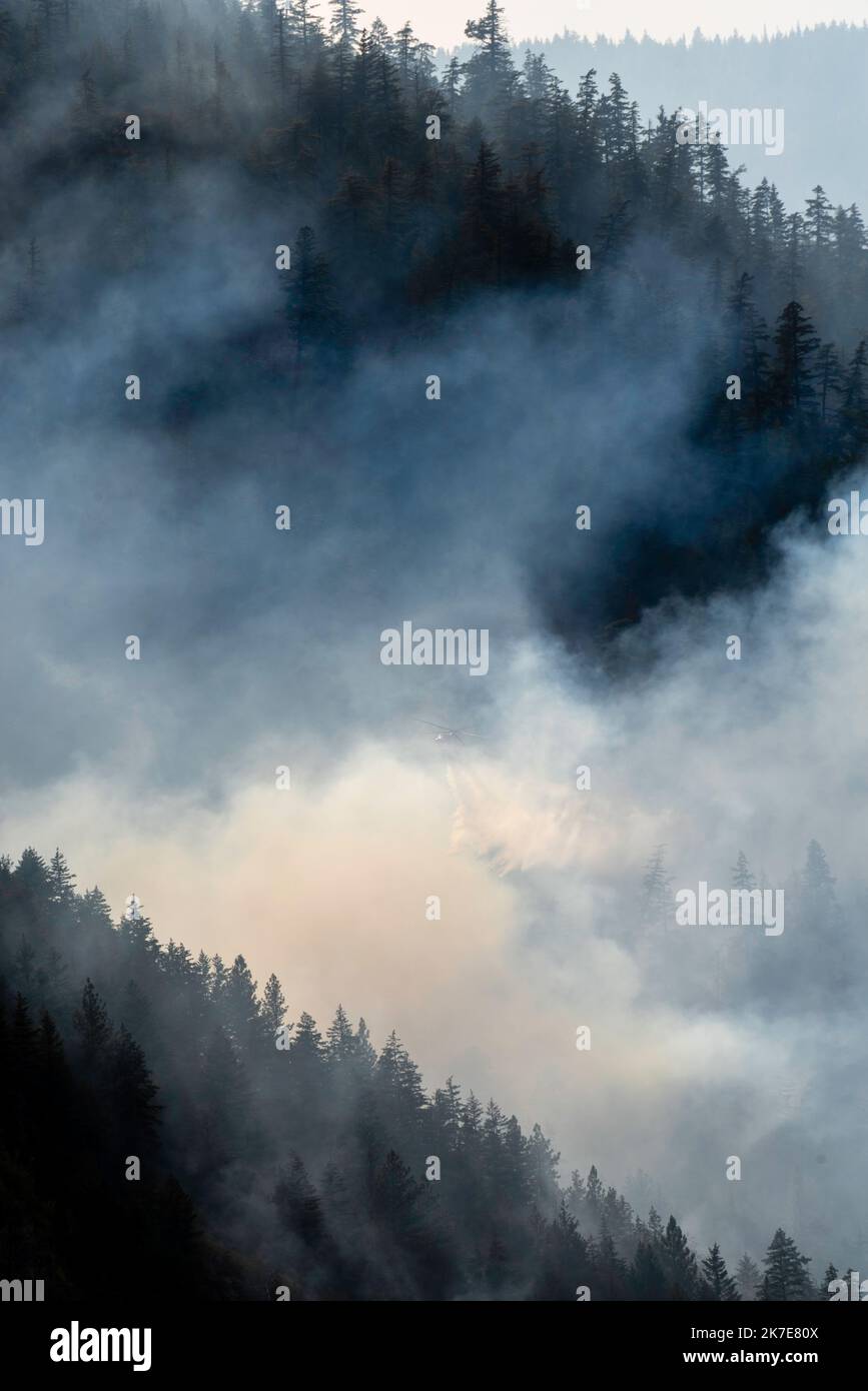 A helicopter drops water on a forest fire burning at the Nohomin Creek ...