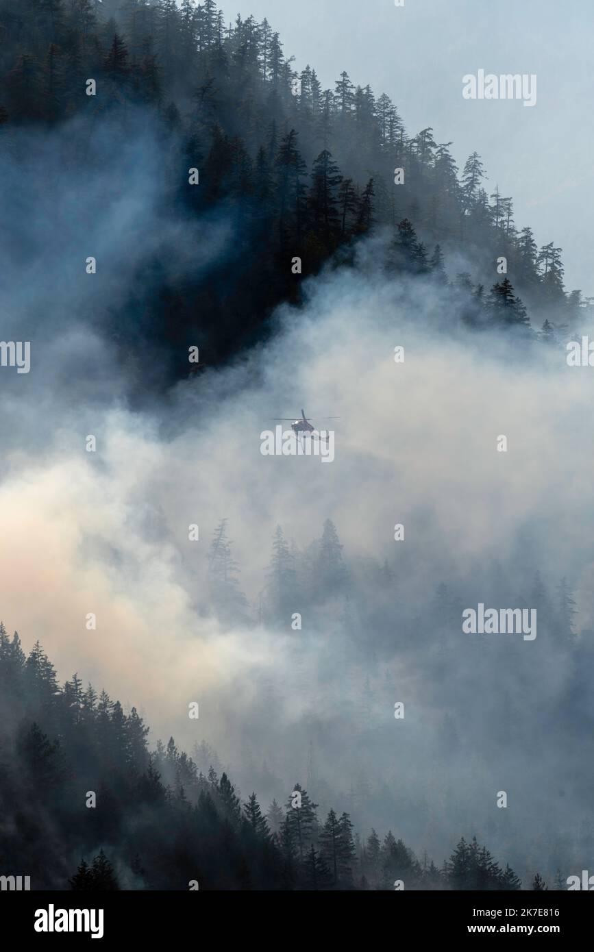 A helicopter drops water on a forest fire burning at the Nohomin Creek ...