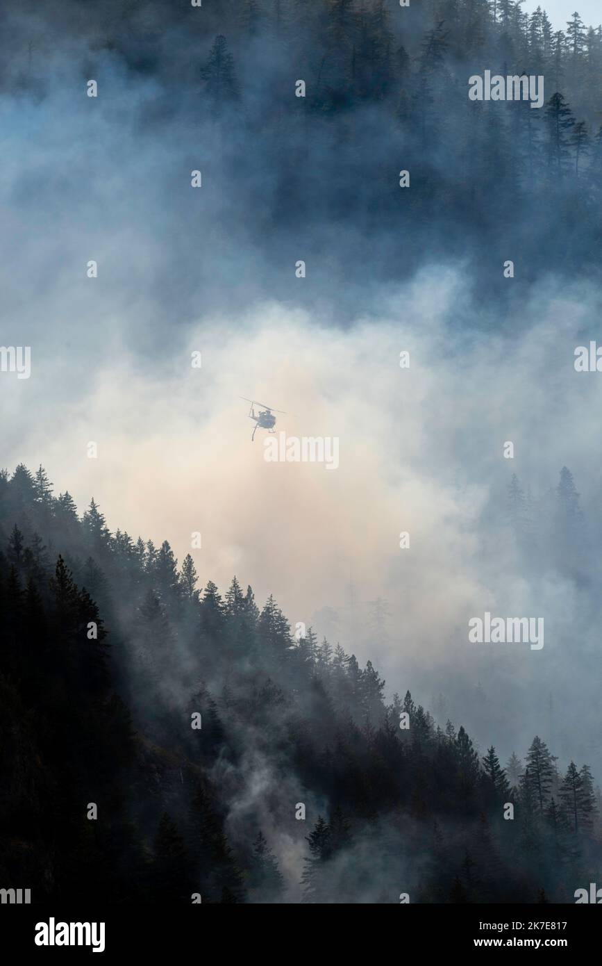 A helicopter drops water on a forest fire burning at the Nohomin Creek ...