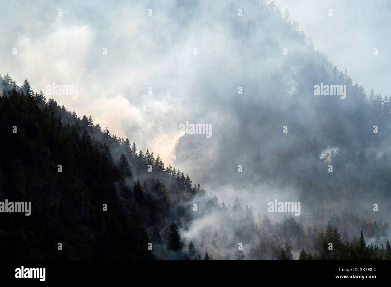 A helicopter drops water on a forest fire burning at the Nohomin Creek ...