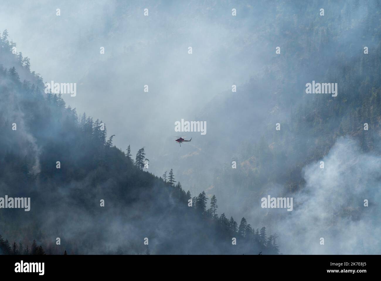 A helicopter drops water on a forest fire burning at the Nohomin Creek ...