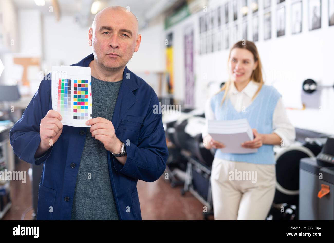 Service engineer demonstrating test page with color palette in his hand ...