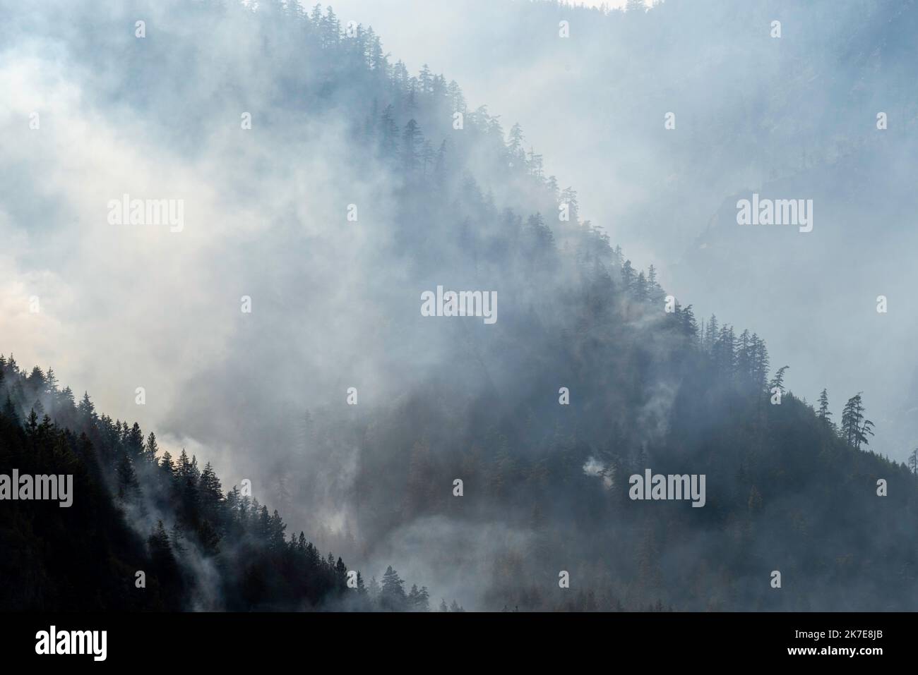 A helicopter drops water on a forest fire burning at the Nohomin Creek ...