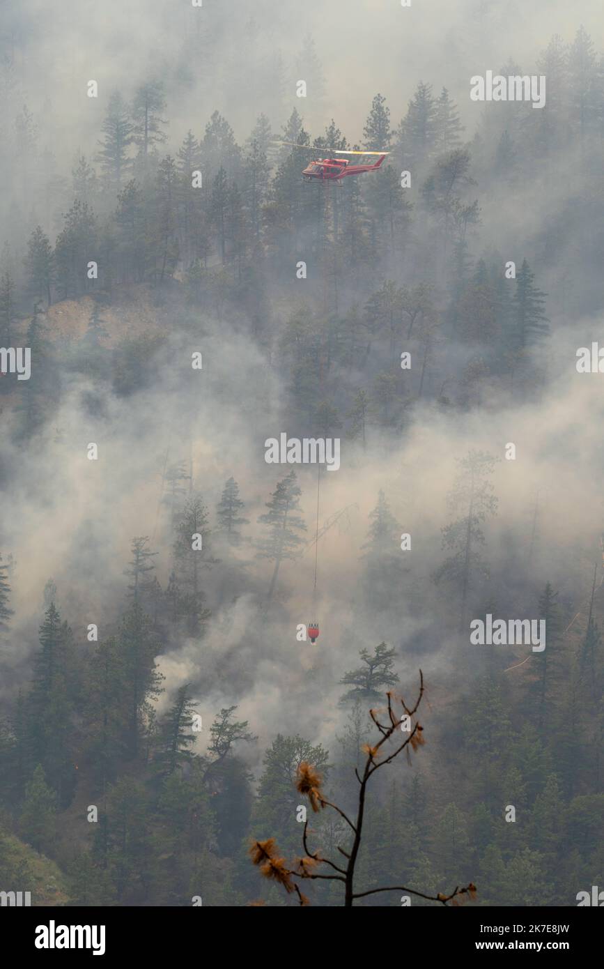A helicopter drops water on a forest fire burning at the Nohomin Creek ...