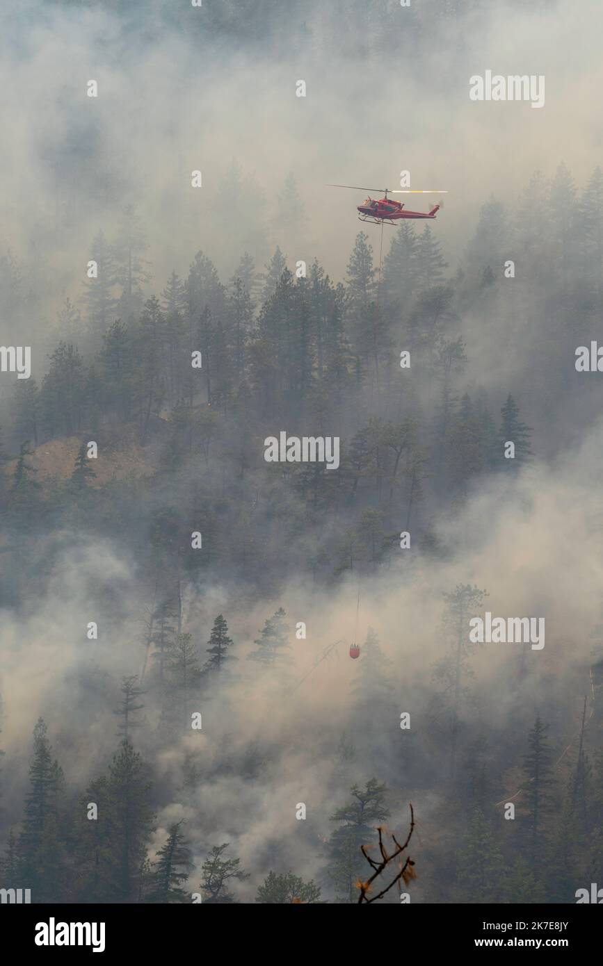 A helicopter drops water on a forest fire burning at the Nohomin Creek ...
