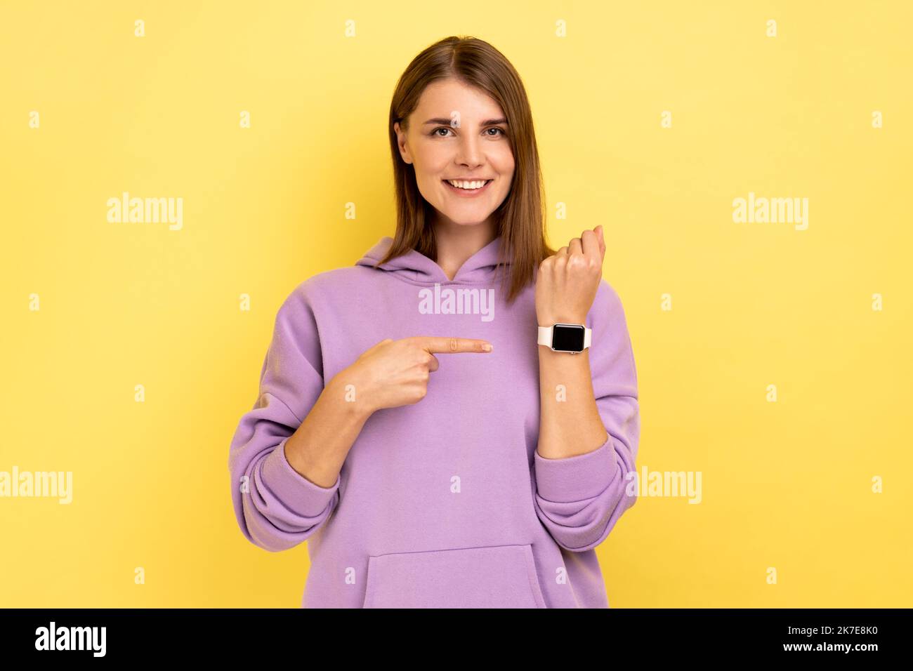 Look at time. Happy positive woman with brown hair pointing finger on ...