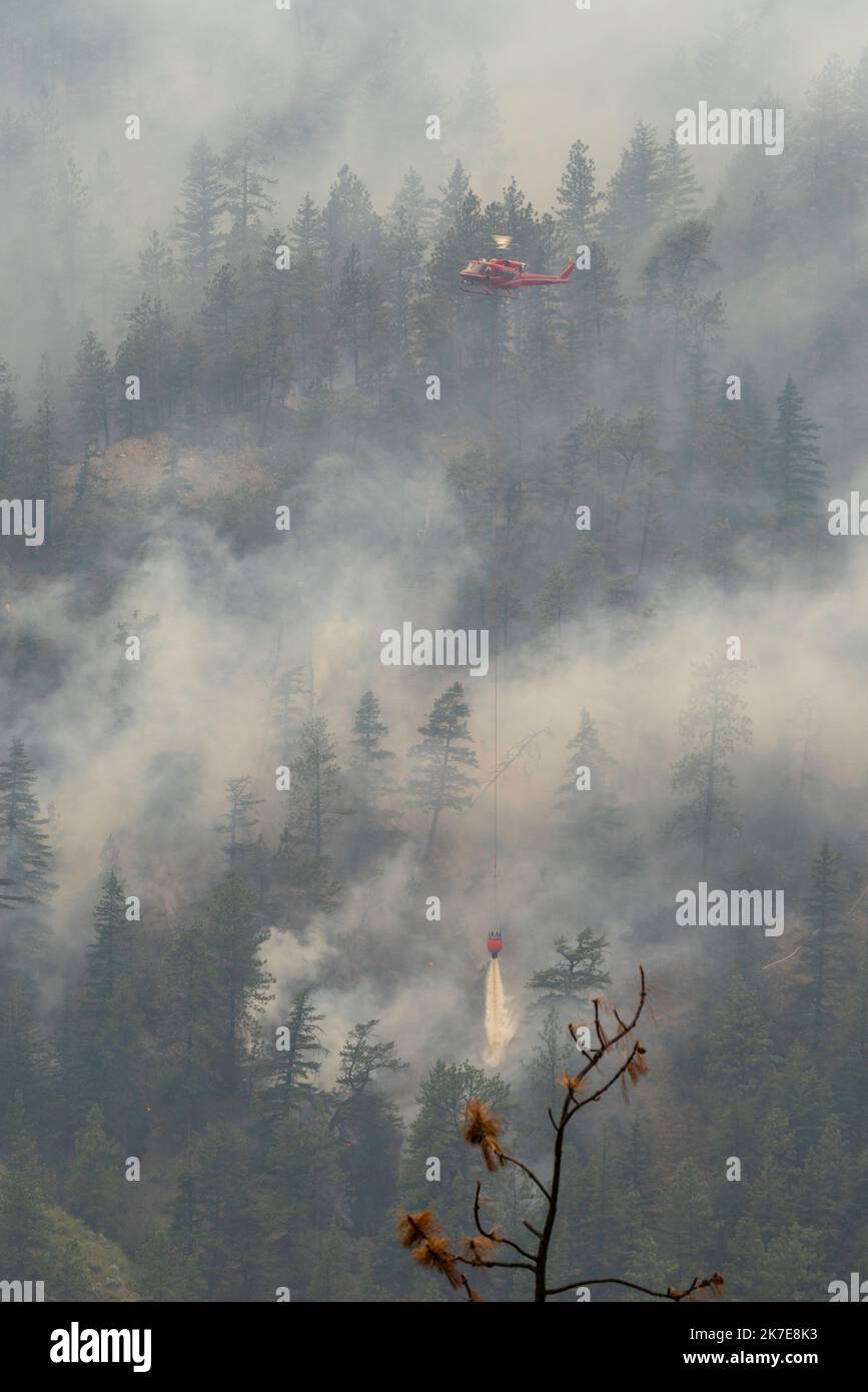 A helicopter drops water on a forest fire burning at the Nohomin Creek ...