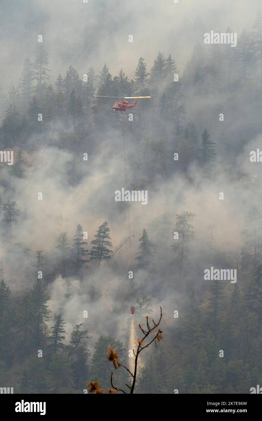 A helicopter drops water on a forest fire burning at the Nohomin Creek ...