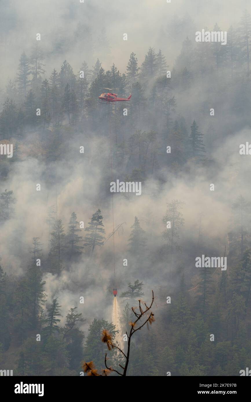 A helicopter drops water on a forest fire burning at the Nohomin Creek ...