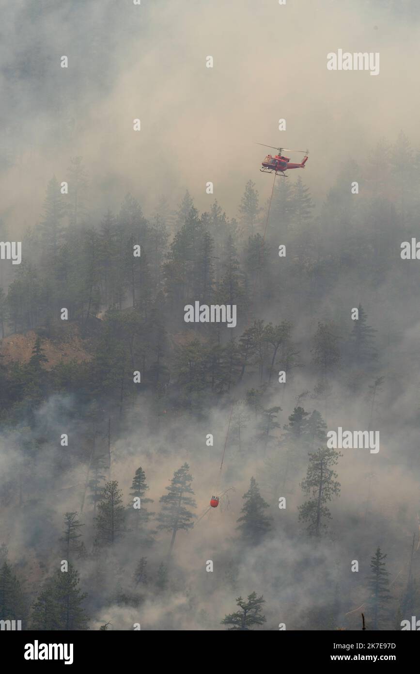 A helicopter drops water on a forest fire burning at the Nohomin Creek ...