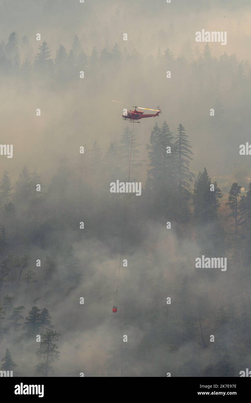 A helicopter drops water on a forest fire burning at the Nohomin Creek ...