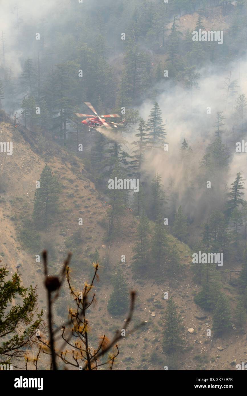 A helicopter drops water on a forest fire burning at the Nohomin Creek ...