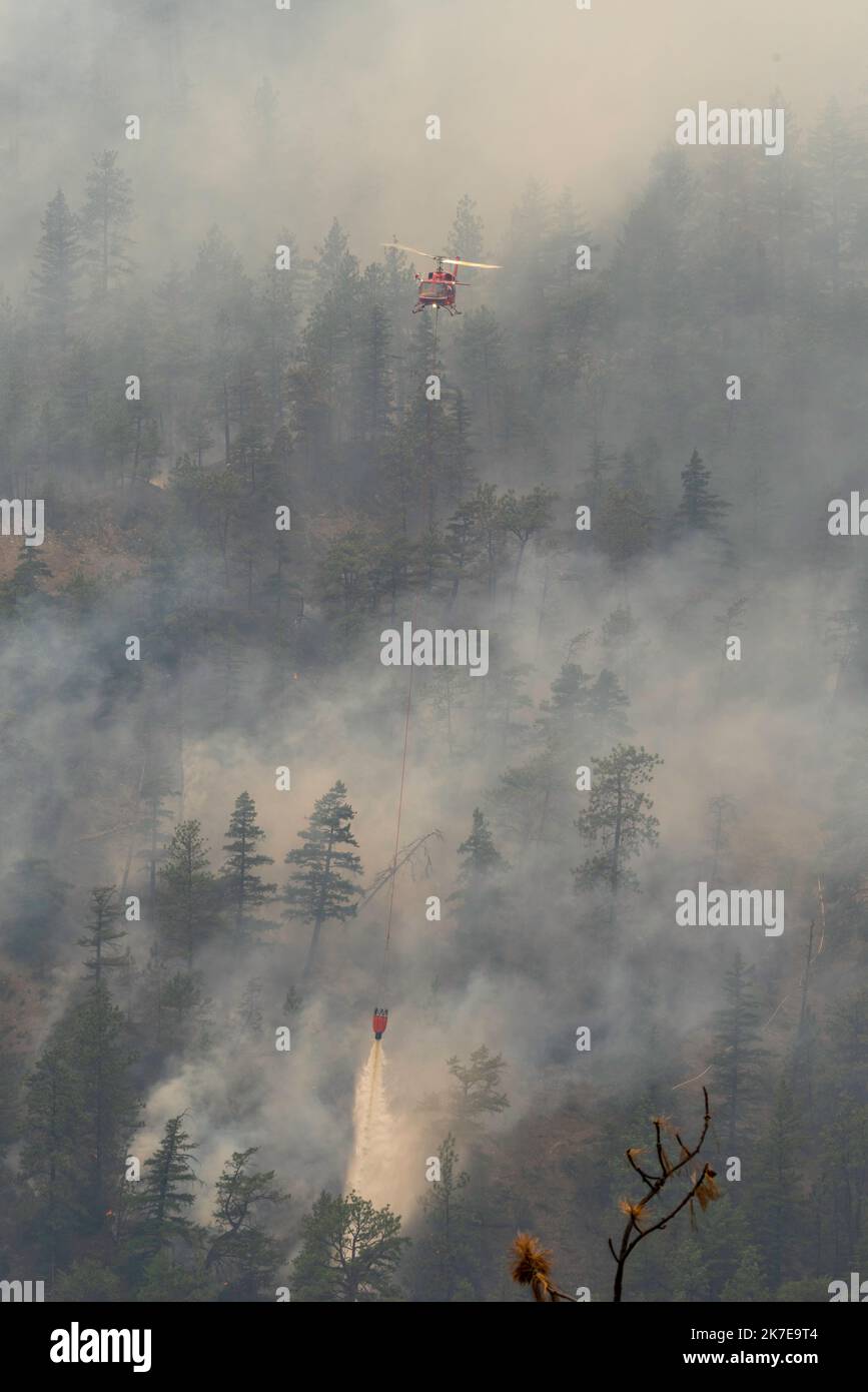 A helicopter drops water on a forest fire burning at the Nohomin Creek ...