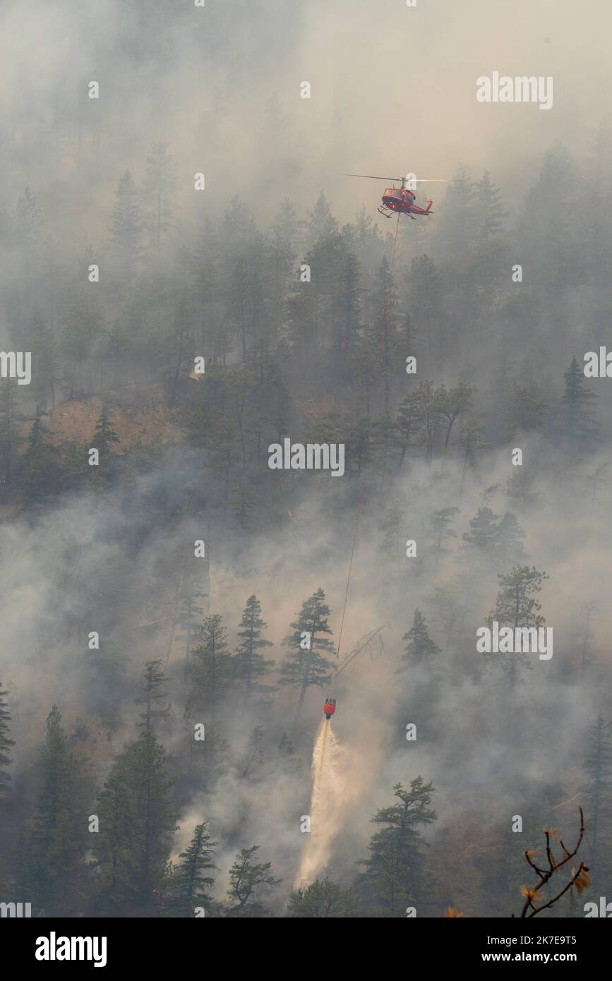 A helicopter drops water on a forest fire burning at the Nohomin Creek ...