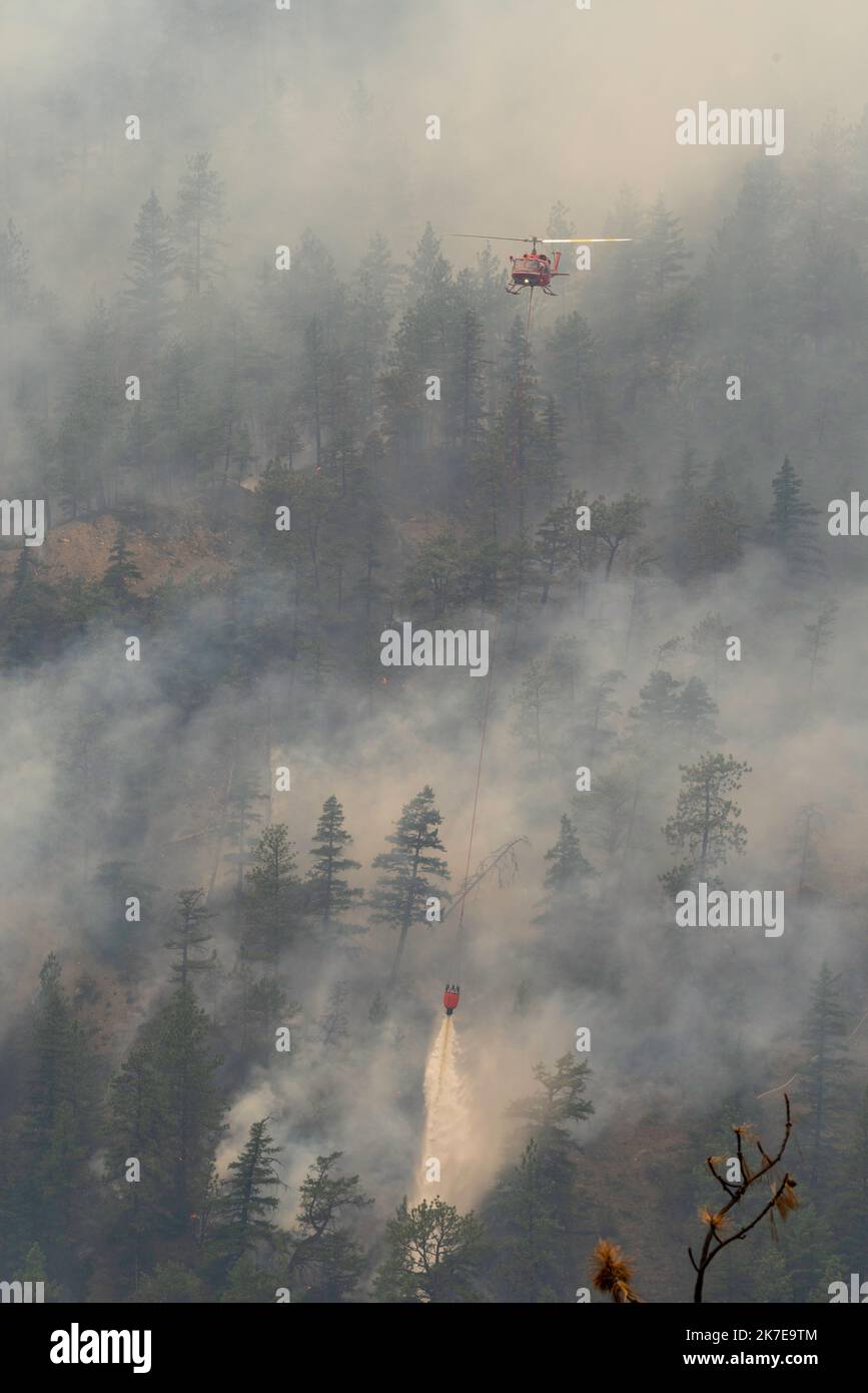 A helicopter drops water on a forest fire burning at the Nohomin Creek ...