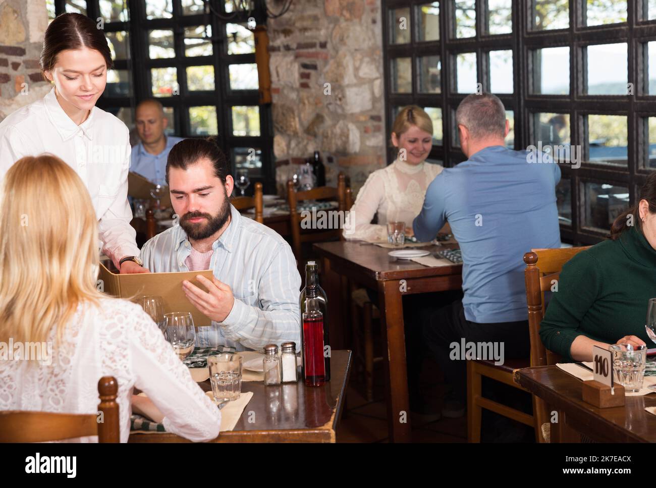 Guests of the country restaurant discuss menu with waitress Stock Photo ...