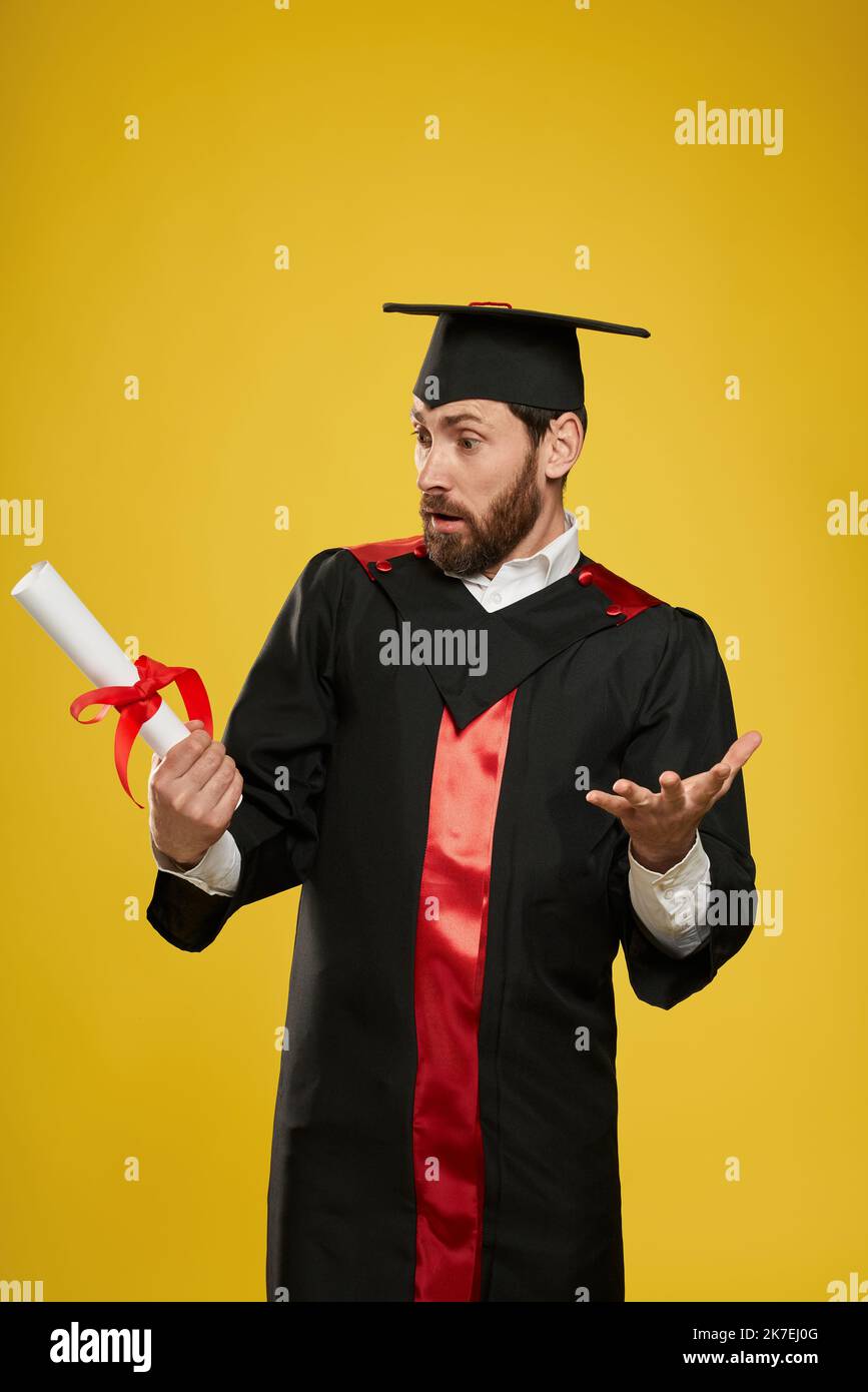 Front view of surprised student holding diploma, asking. Handsome ...