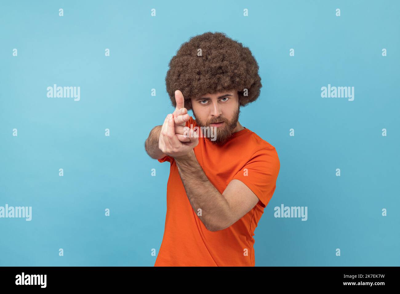 Portrait of serious man with Afro hairstyle wearing orange T-shirt ...