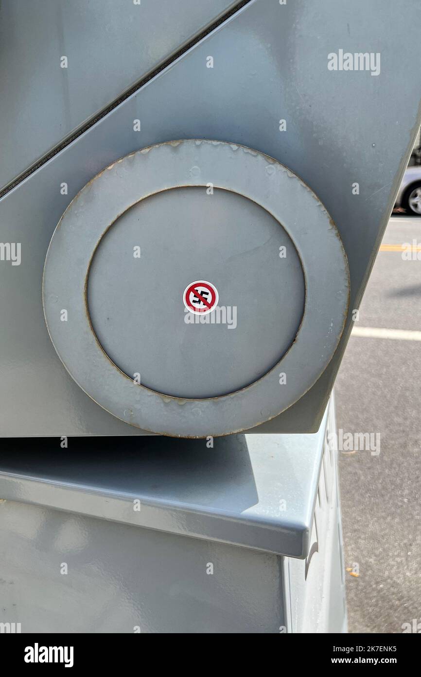 A small round sticker with a red line through a Nazi swastika is stuck ...
