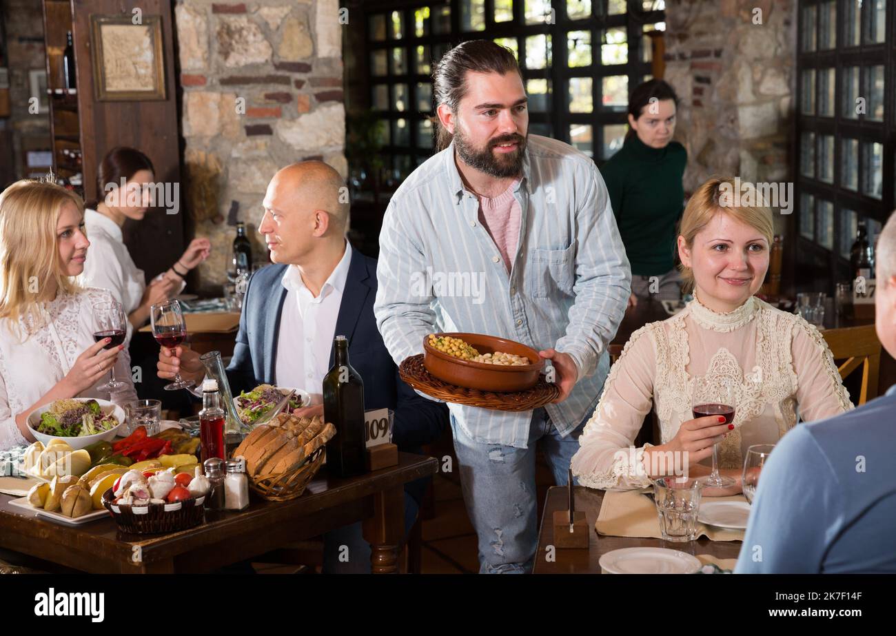 Waiter placing order in front of guests in country restaurant Stock ...