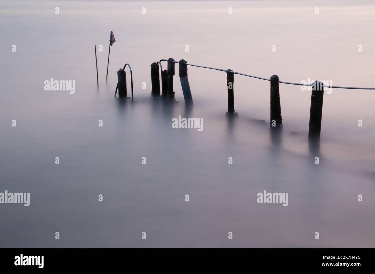 Old damaged concrete and metal pier partially submerged with a silky ...