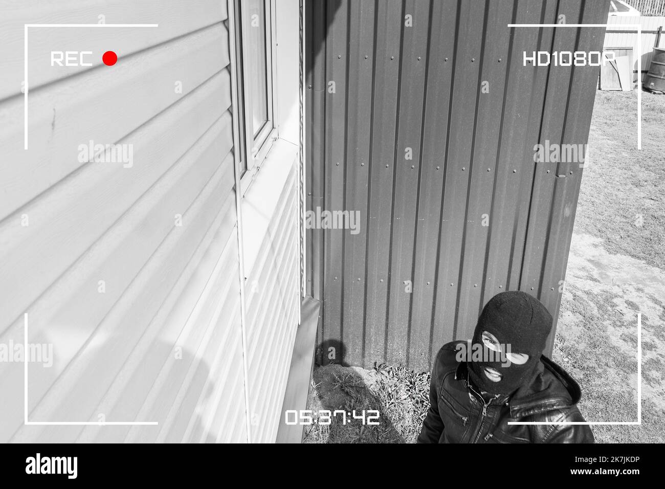 A man in a black mask is trying to rob a house. simulation of recording ...