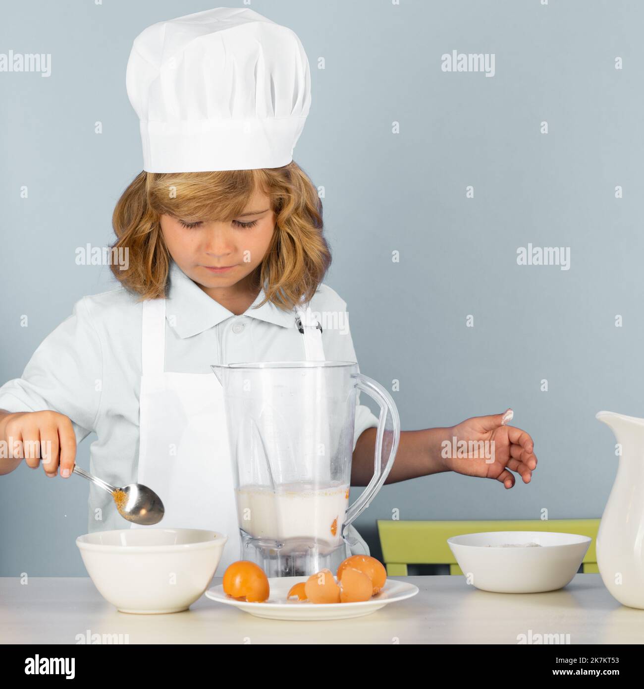 Child chef cook prepares food on isolated grey studio background. Kids ...