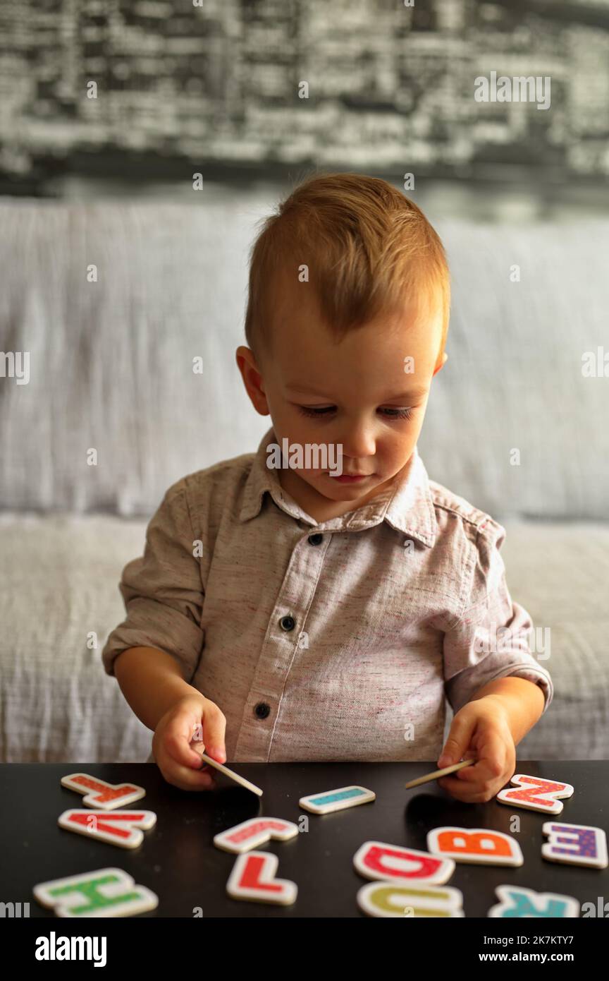 Portrait of cute little boy playing with letters and numbers on a table ...