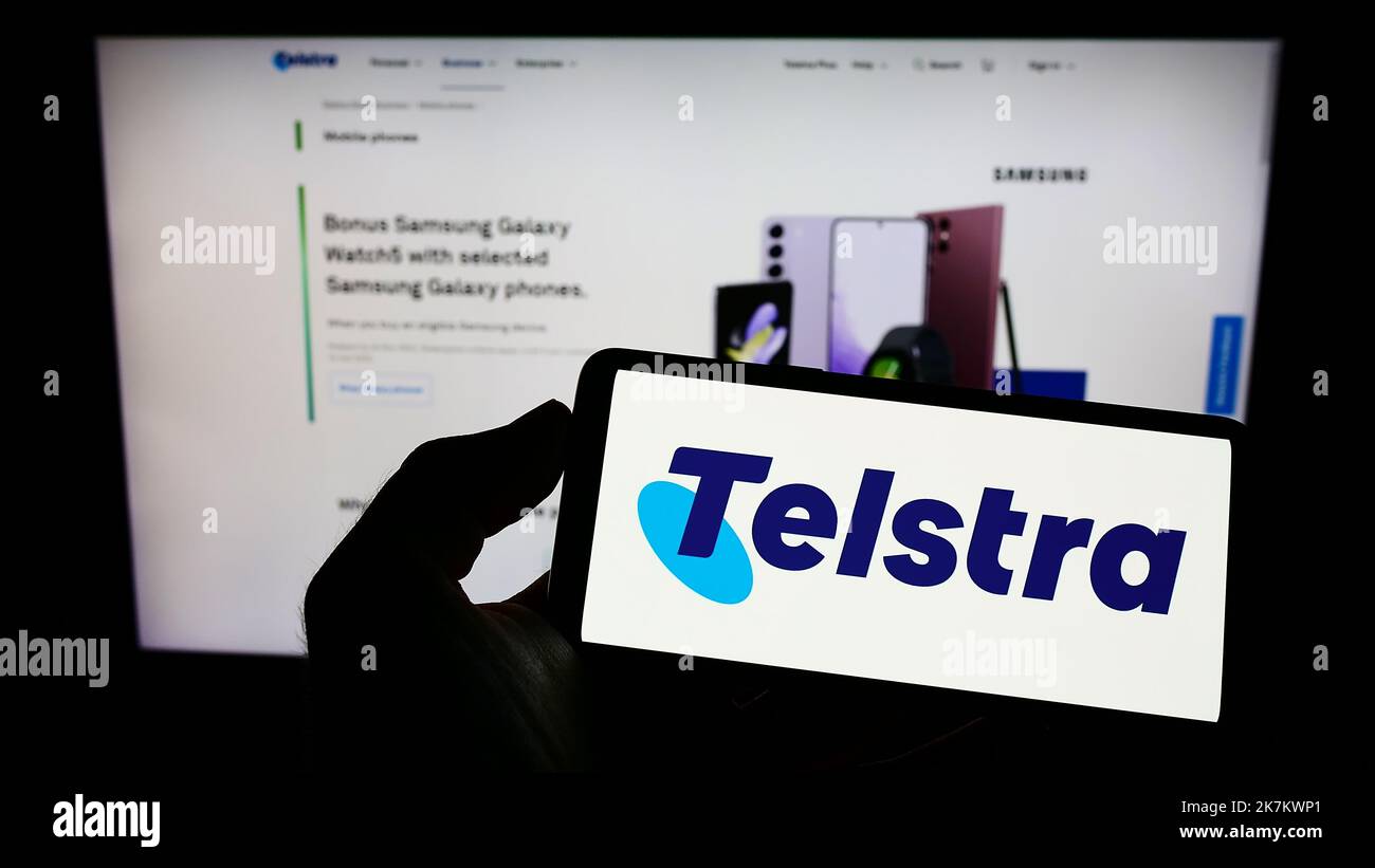 Person holding mobile phone with logo of Australian company Telstra ...