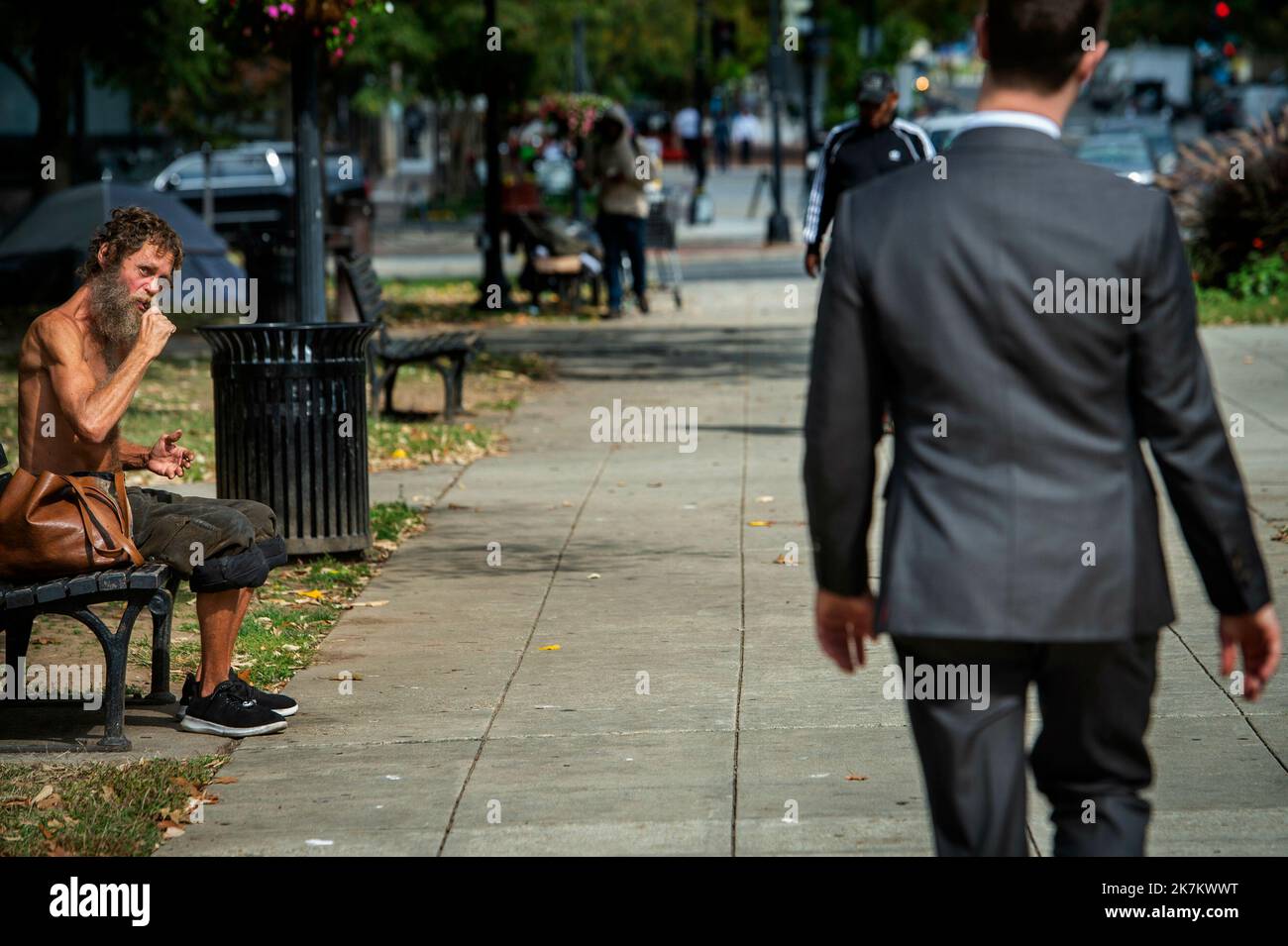 During the lunch hour, people pass by a man brushing his teeth in a ...