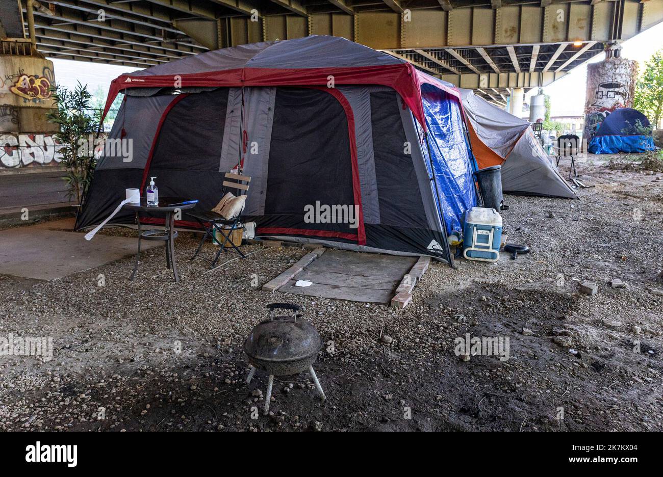 A grill can be seen in front of a tent in a homeless encampment under ...