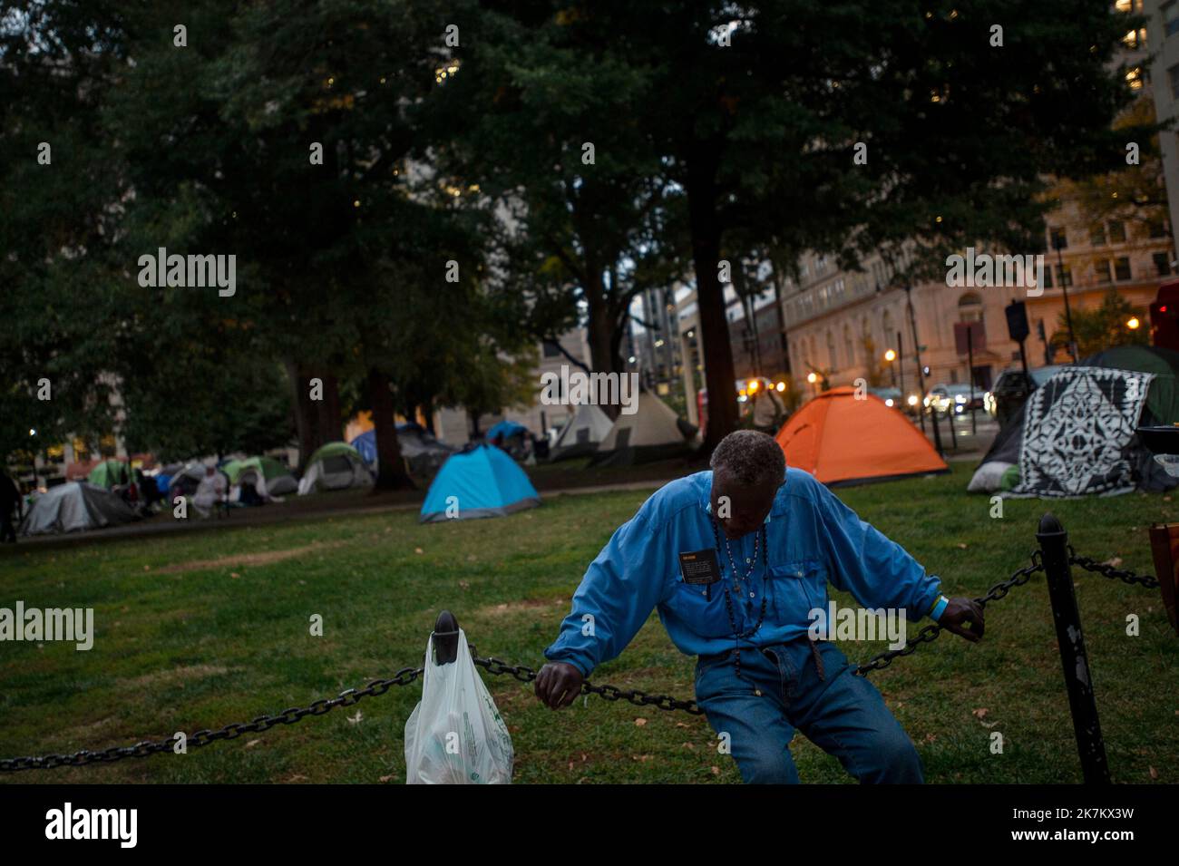 A man rests upon a chain link post while volunteers from Martha s Table ...