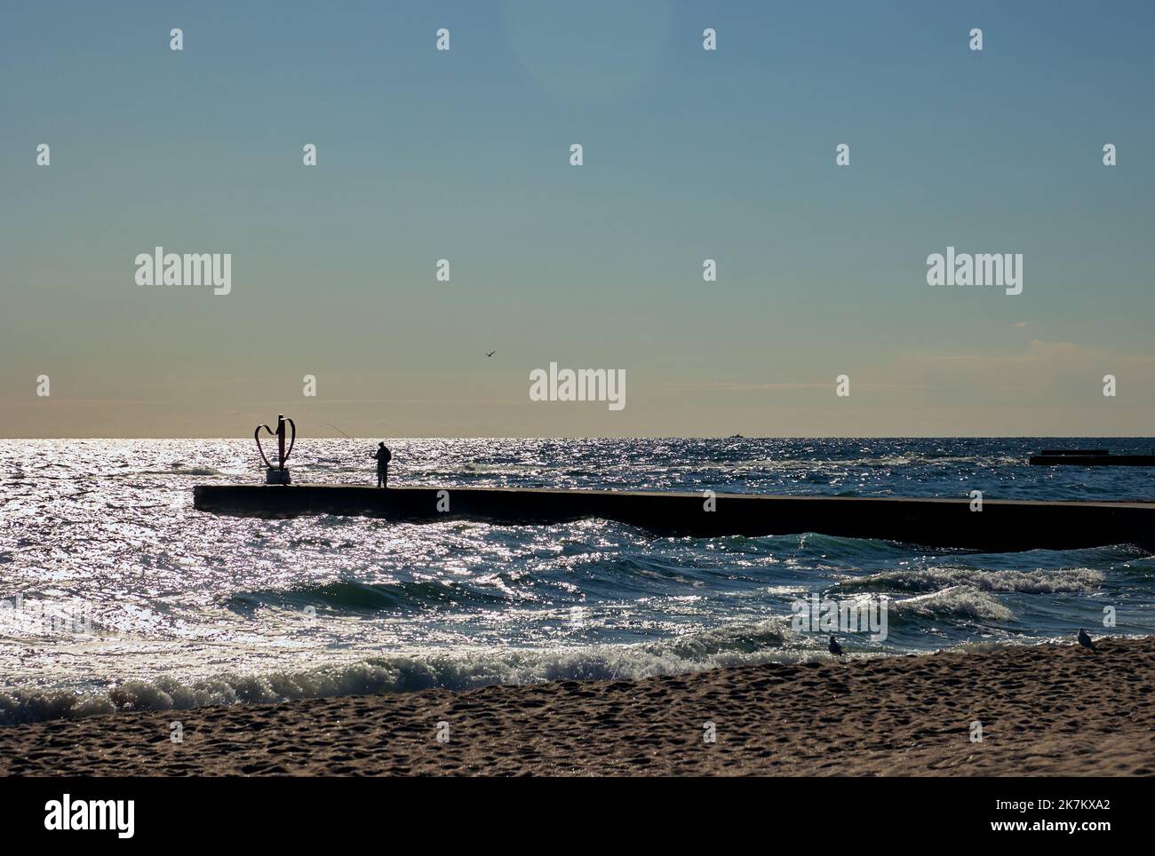 Sea landscape with pier goes out to sea and fishermen are fishing at ...