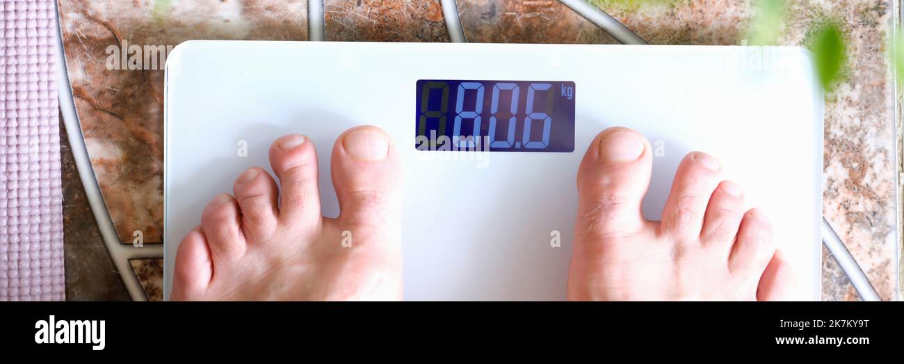 Man stands on scales on scales figure 80 kilograms Stock Photo - Alamy