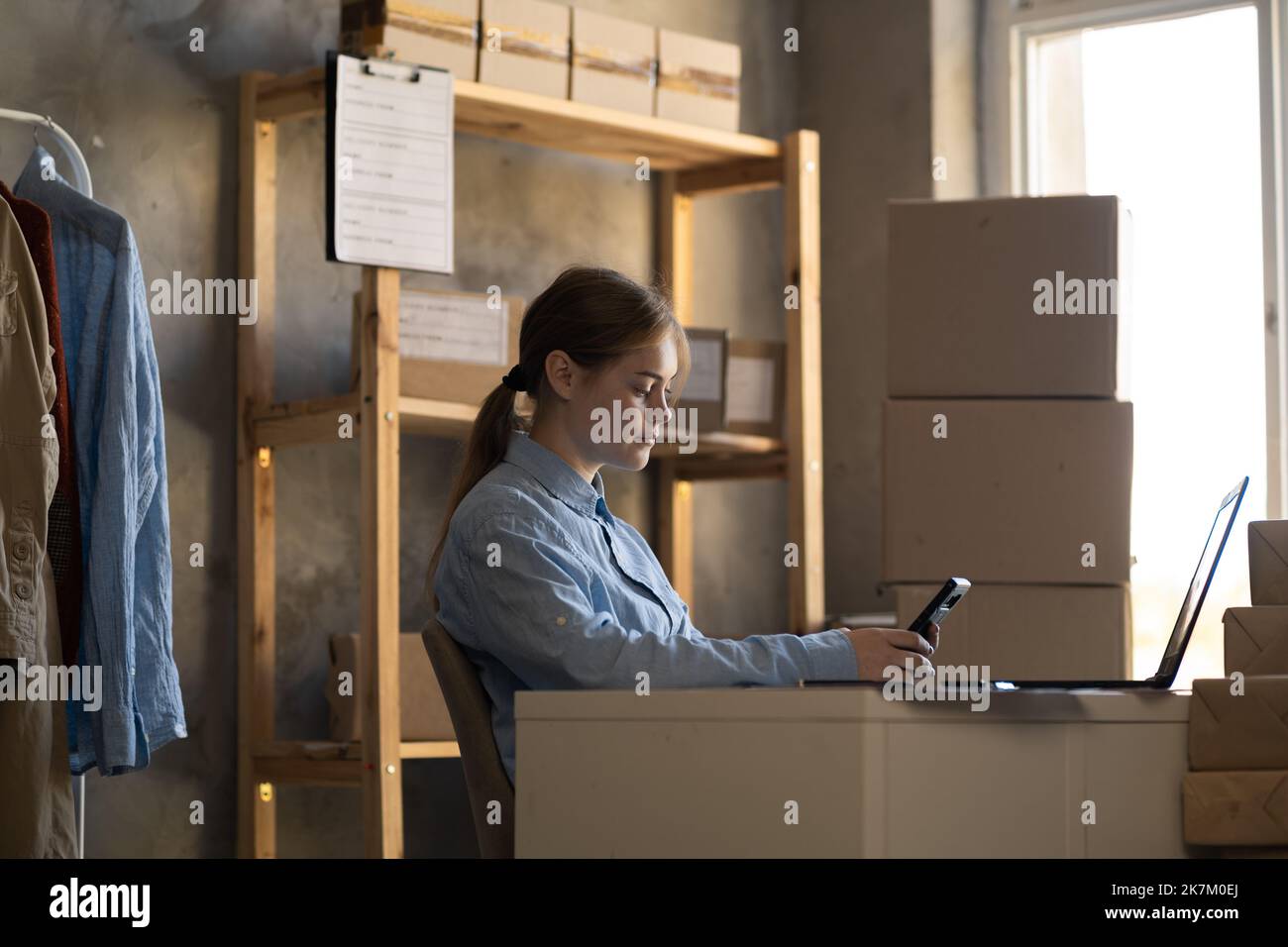Female warehouse worker manager, small business owner holding phone ...
