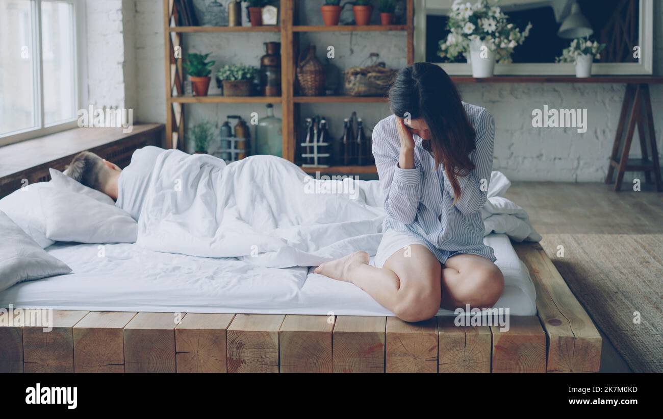 Sad young woman is sitting on bed and crying after fight with her ...