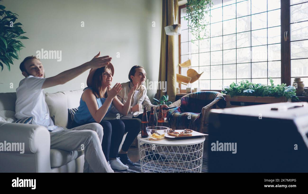 Happy friends excited sports fans are watching games on TV in the house ...