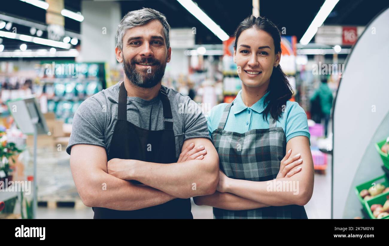 Portrait of two supermarket employees attractive young people in aprons ...