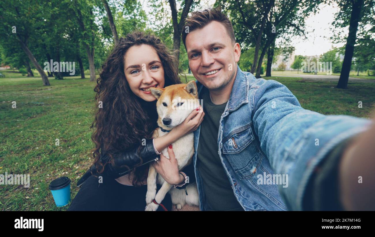 Young wife and husband are taking selfie with adorable dog and hugging ...