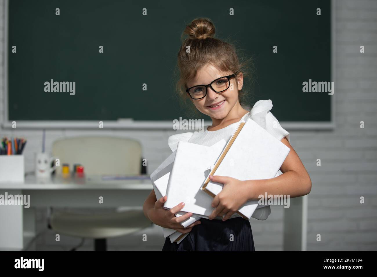 Cute little school kid girl with books in a classroom. Elementary ...