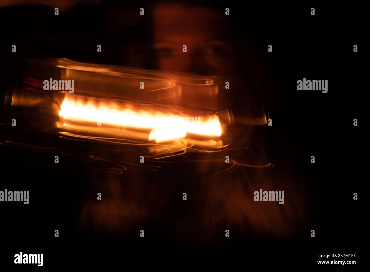 A young Ukrainian girl with a kerosene lamp in the dark sits at home ...