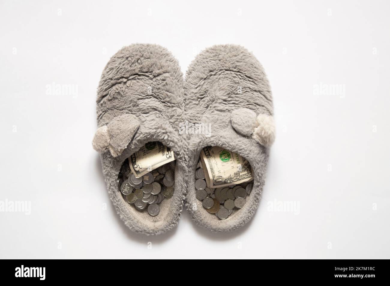 pennies and dollars lie in gray slippers on an isolated white ...