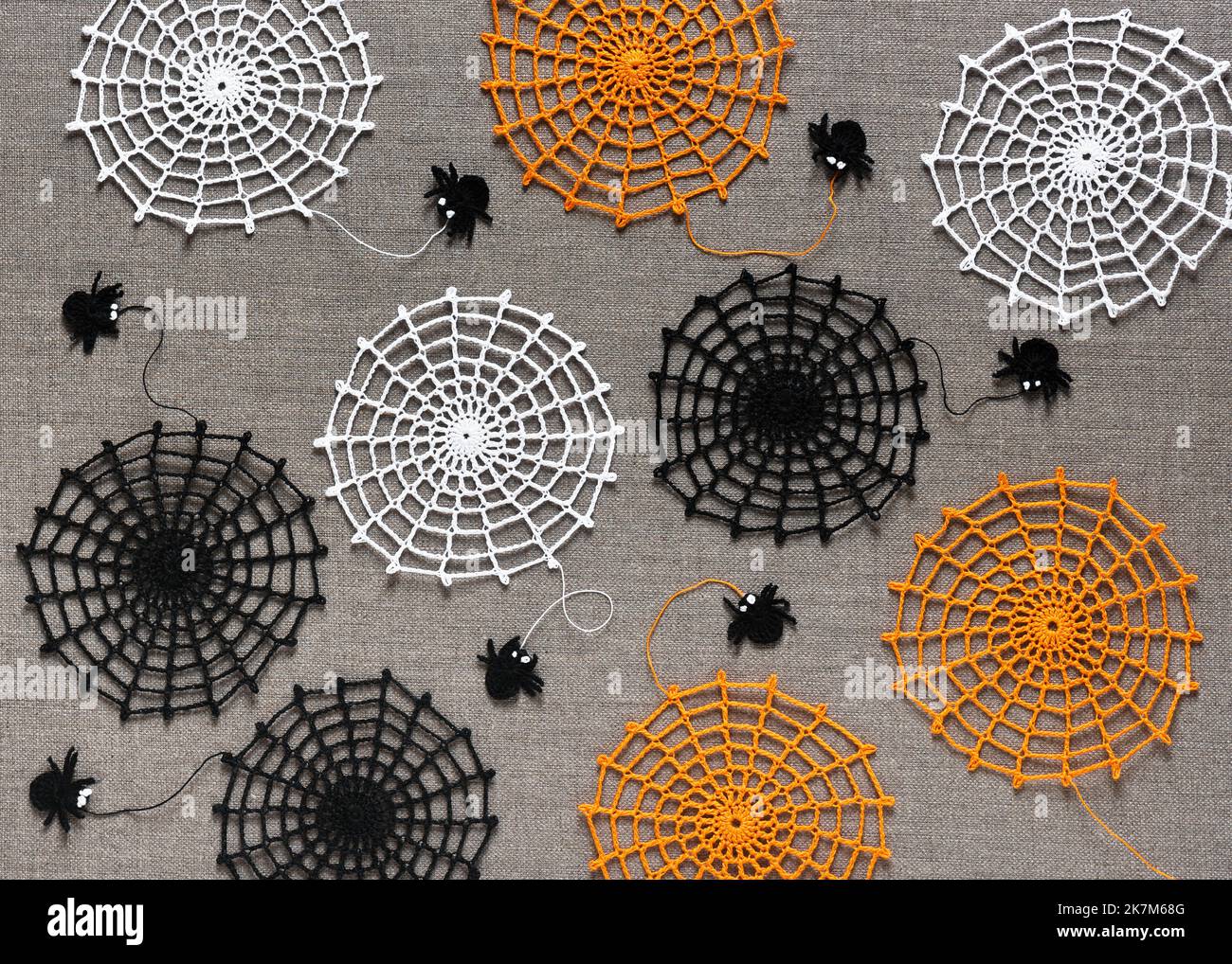 Crocheted colorful cobwebs with black funny spiders on nature linen ...